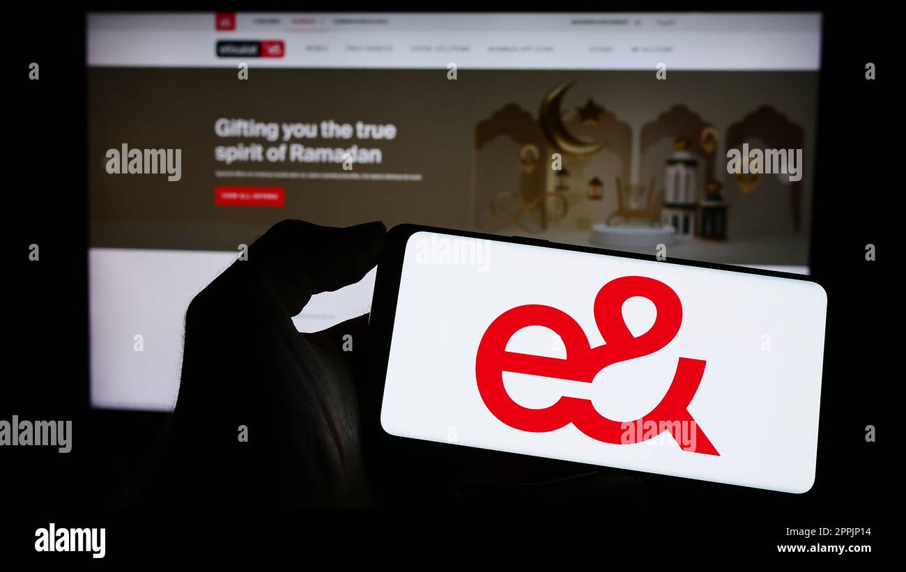 Person holding cellphone with logo of Emirates Telecommunications Group ...