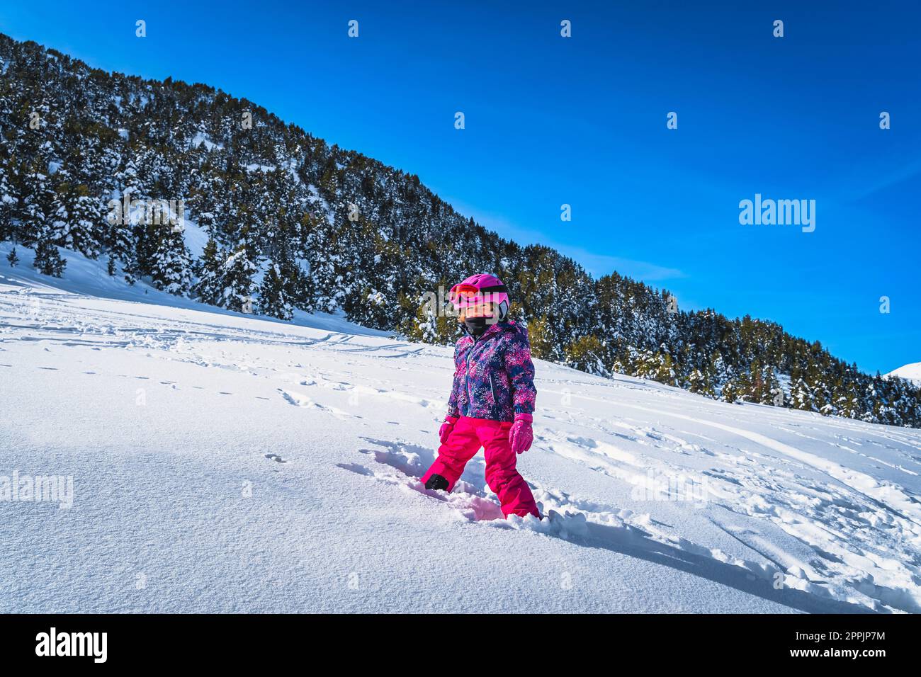 Girl standing in deep snow with mountains and forest in a background ...