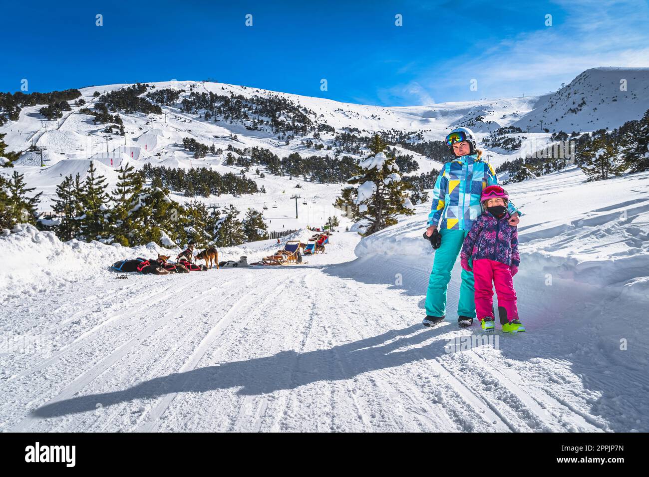 Mother and daughter on snowy road, dog sledding, mountains and forest ...