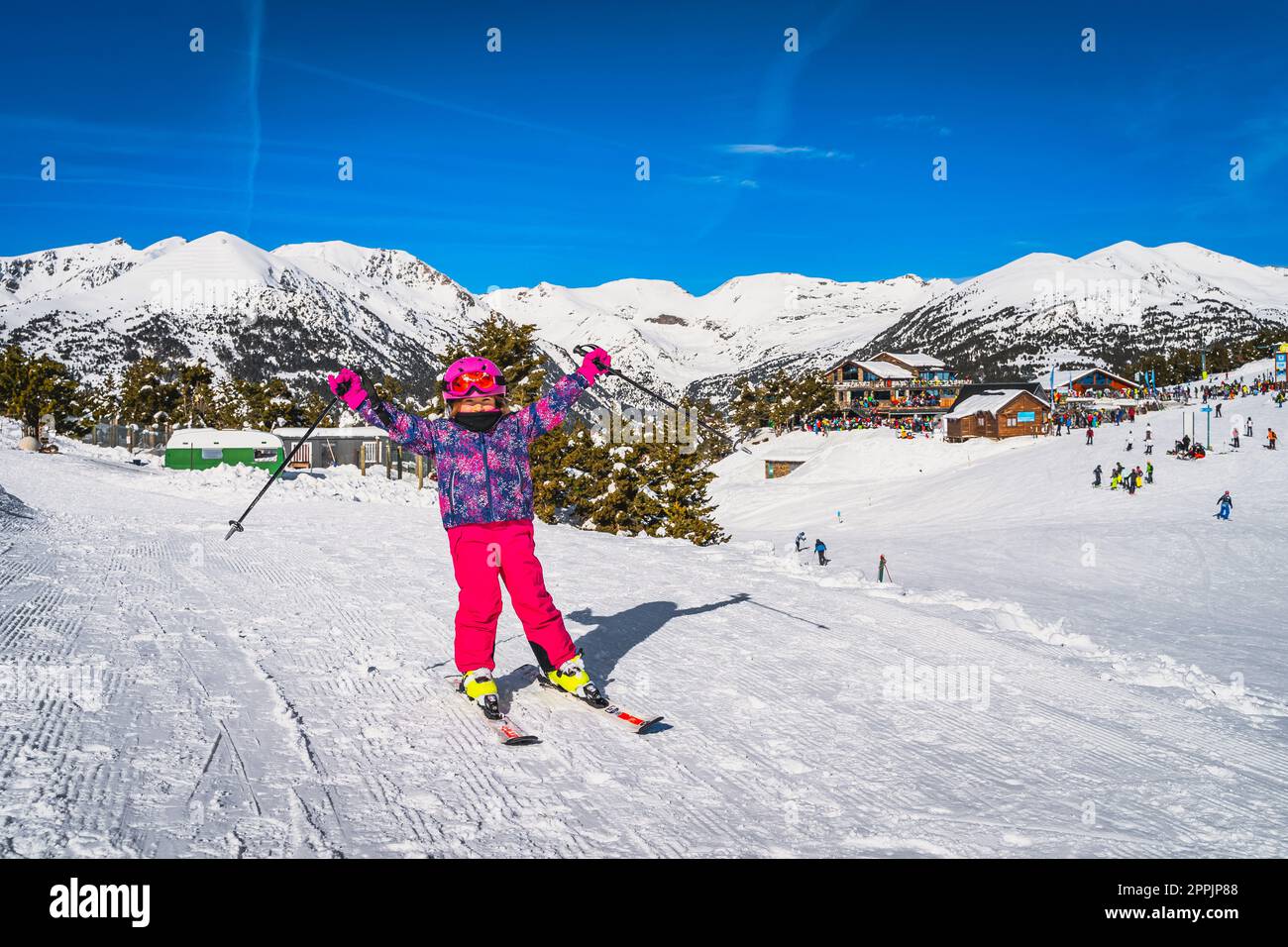 Young girl on a ski lifting her hands up in a cheer with ski resort and ...