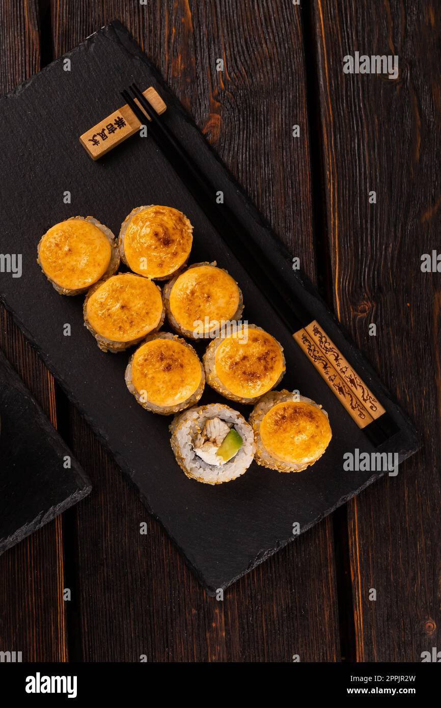 Sushi roll with eel, avocado and cream cheese served on black board top ...