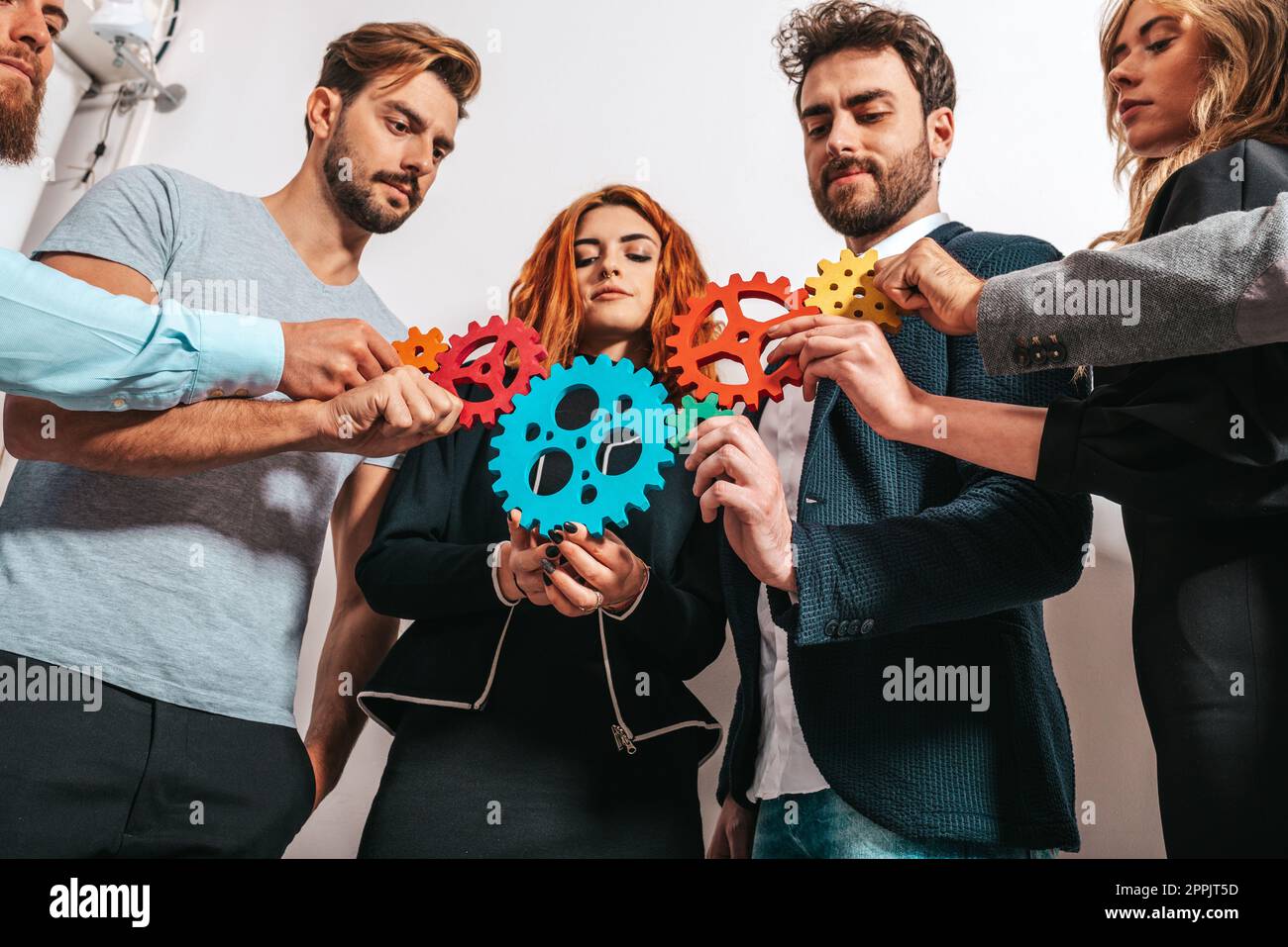Teamwork of businesspeople work together and combine pieces of gears as ...