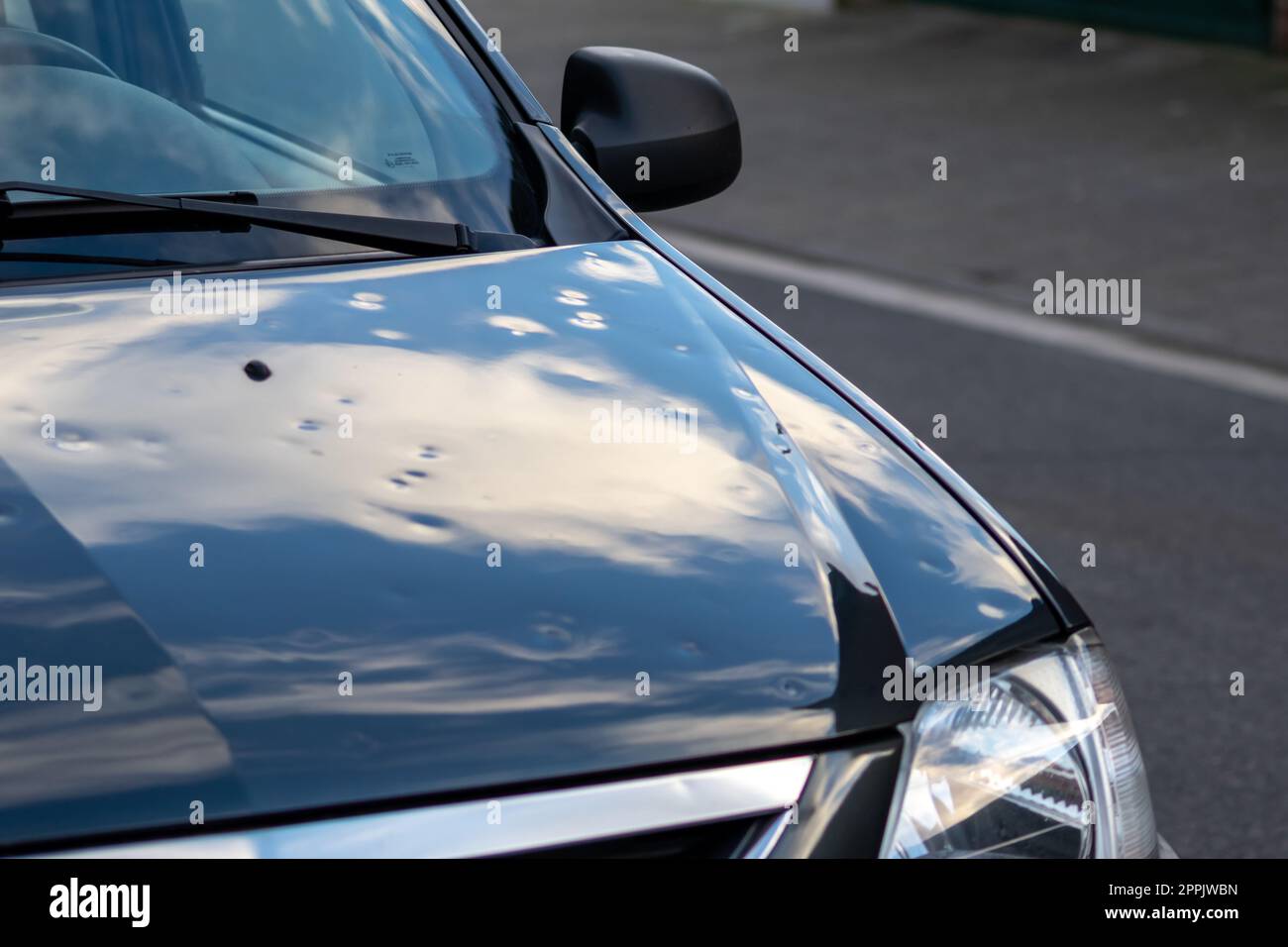 Black car engine hood with many hail damage dents show the forces of ...