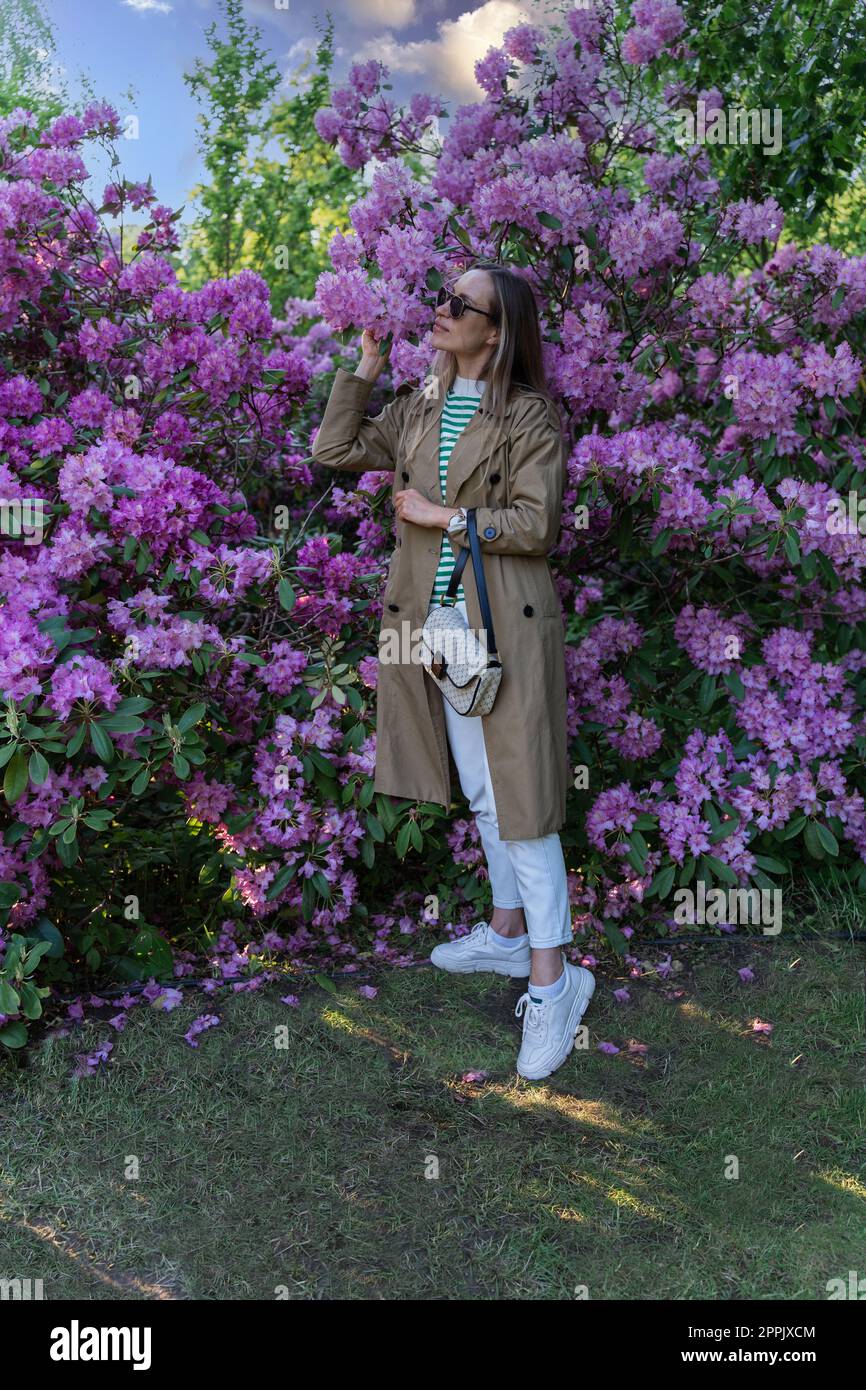 A woman smells purple flowers on a rhododendron bush Stock Photo - Alamy