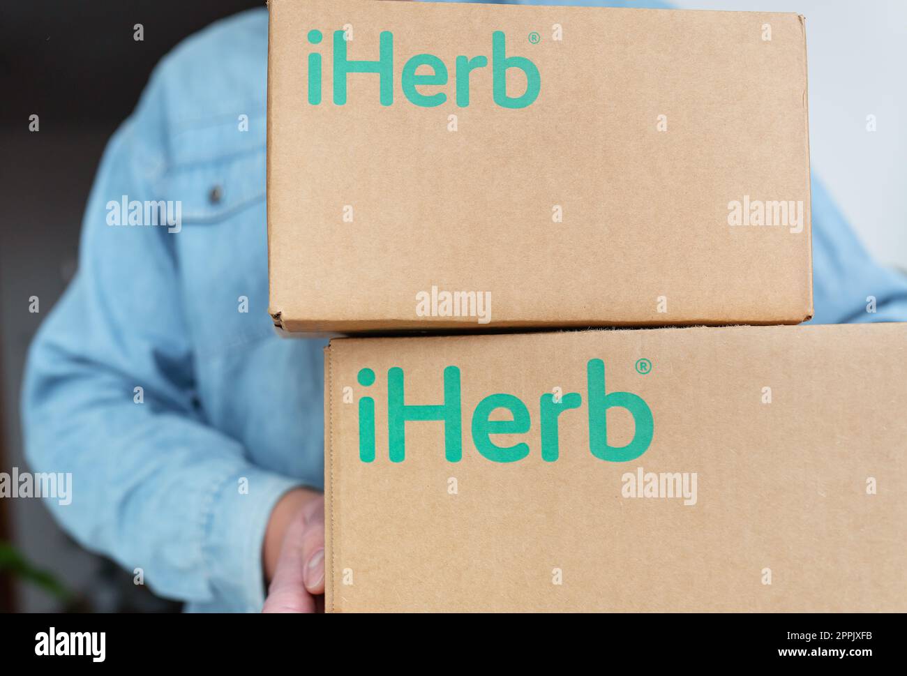 Kyiv, Ukraine-December 17, 2022: . IHerb box packaging in the hands of the courier, fast ...