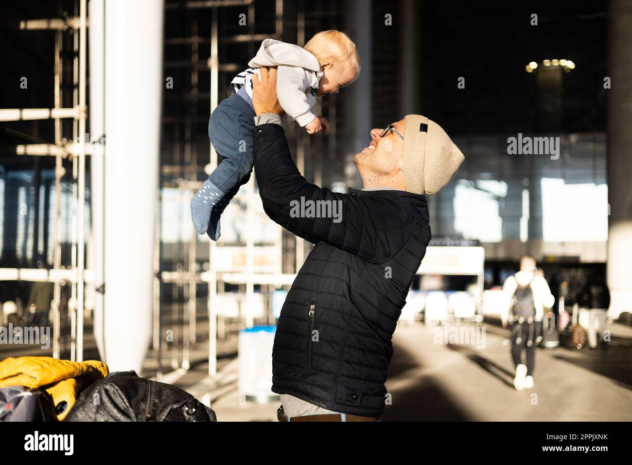 Father happily holding and lifting his infant baby boy child in the air ...