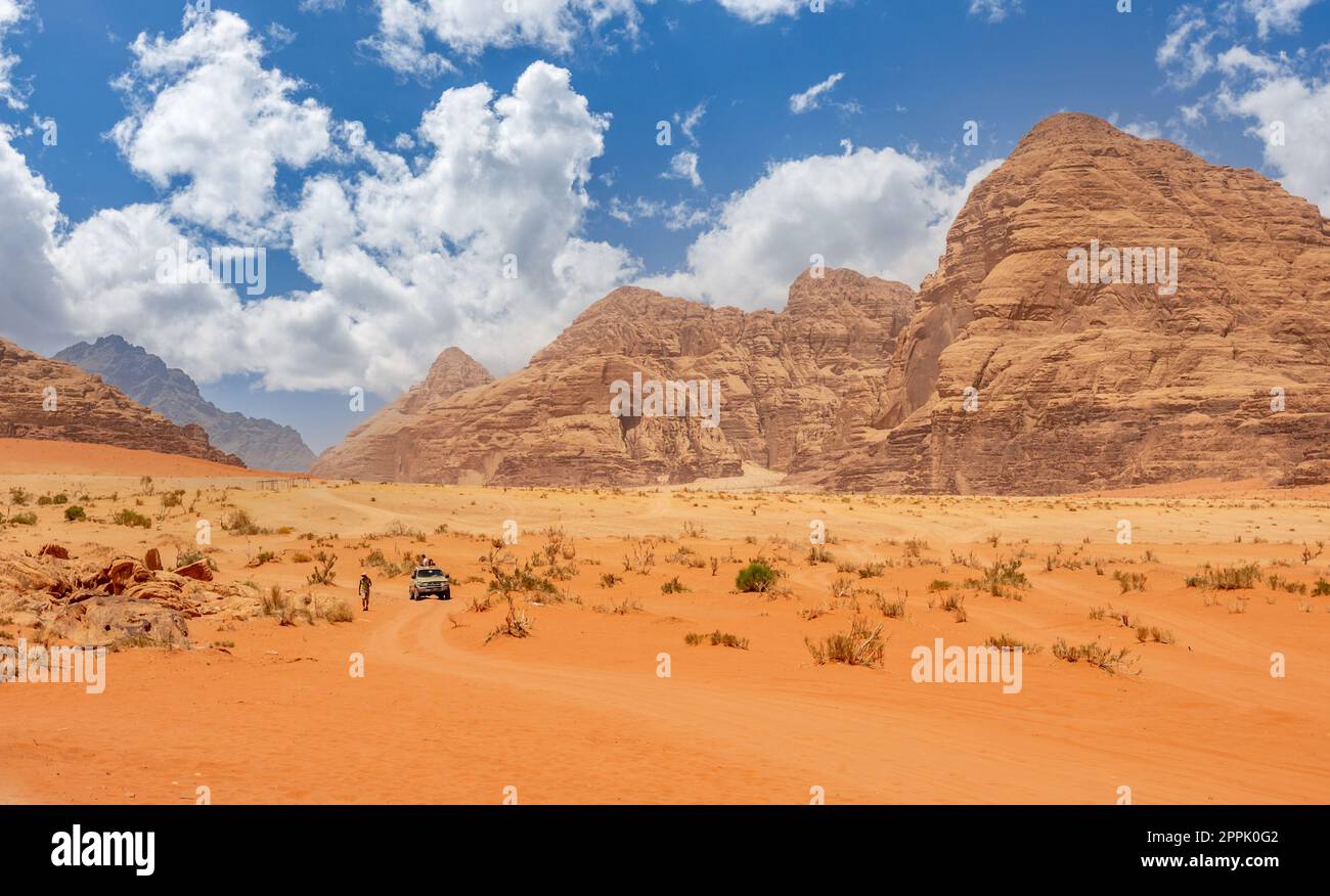 Orange sands and cliffs of Wadi Rum desert with tourist car in the ...