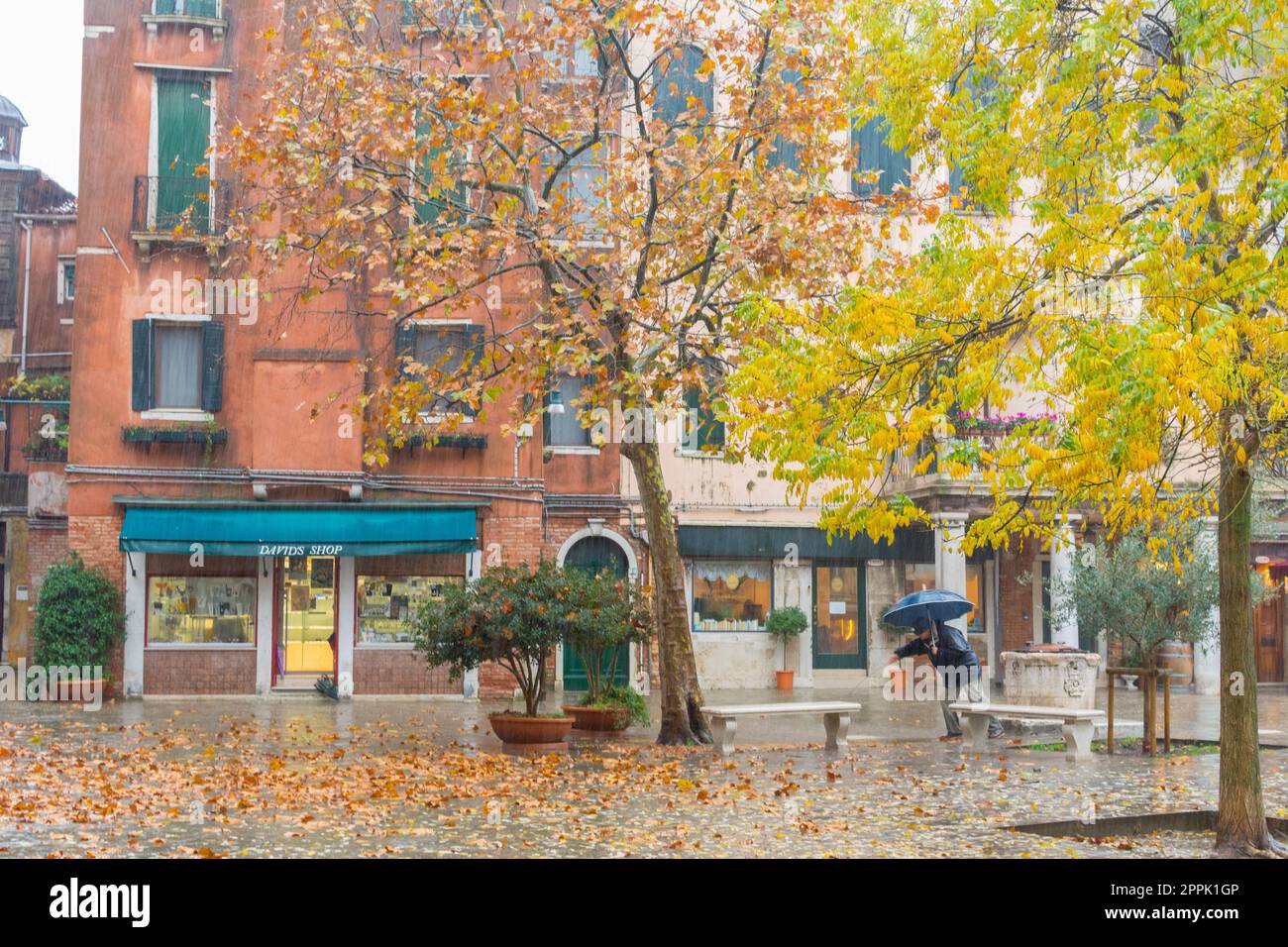Rain in Vencie: old man making his way through a rain storm in autumn ...