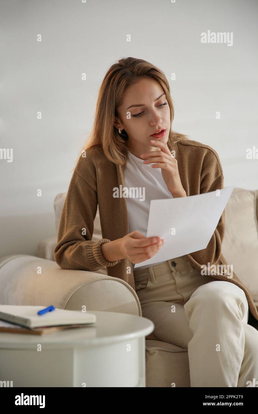 Woman reading letter on sofa at home Stock Photo - Alamy
