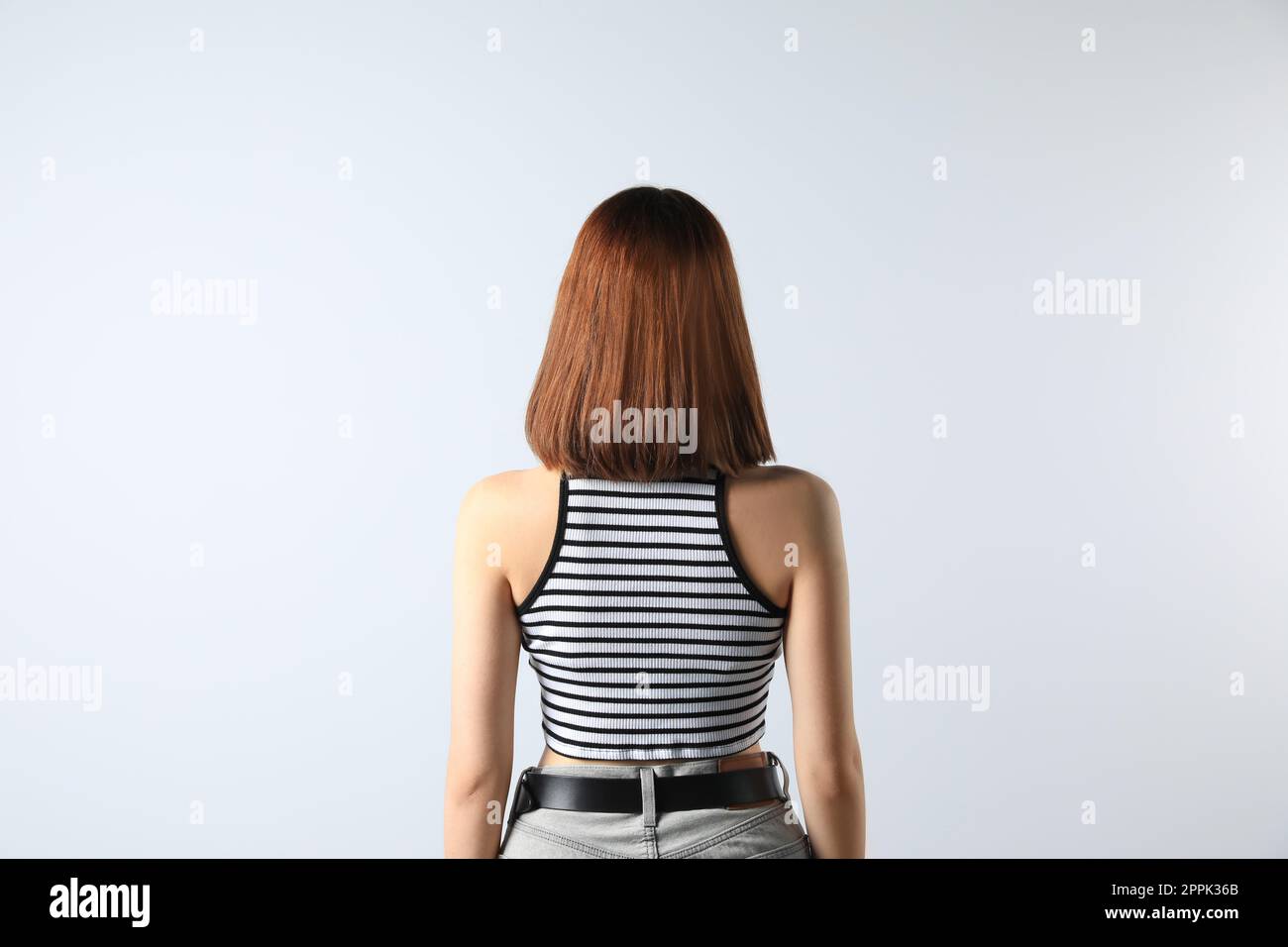 Girl wearing striped top on white background, back view Stock Photo - Alamy