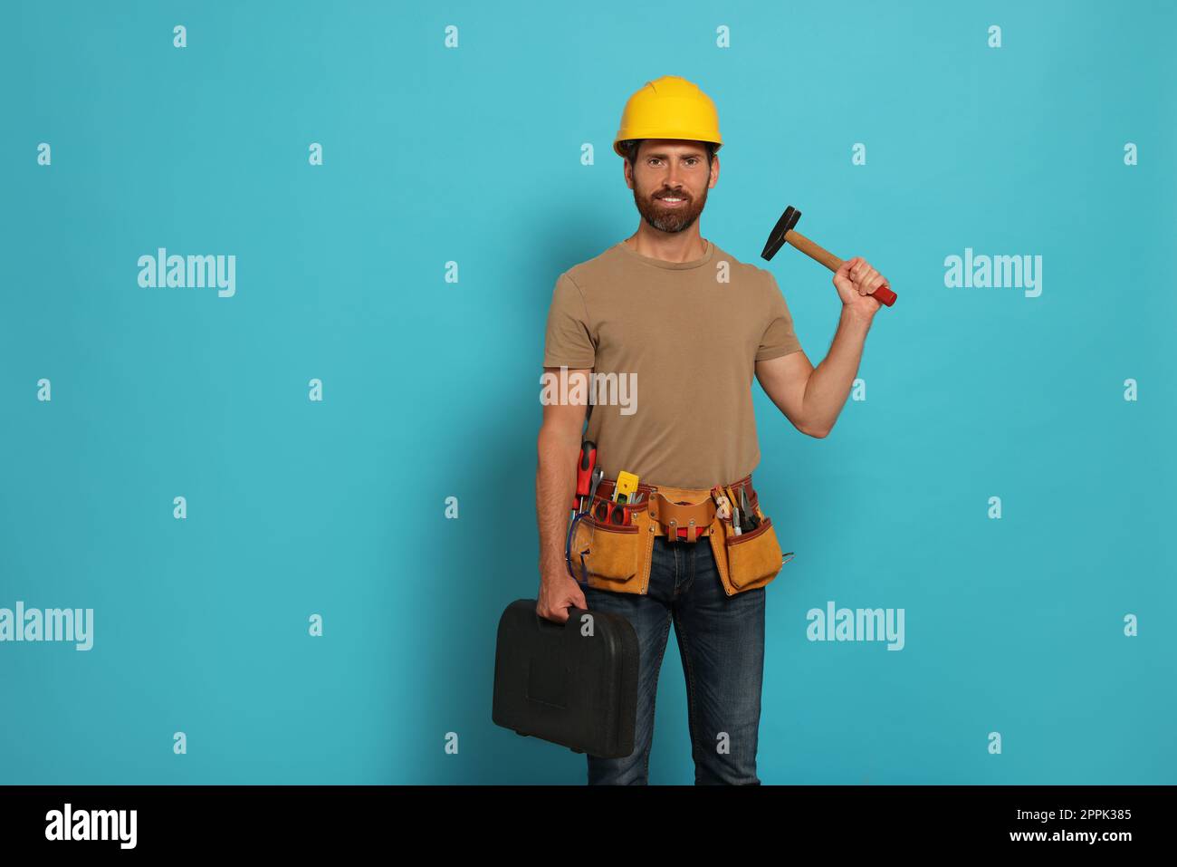 Professional builder in hard hat with hammer and tool belt on light ...