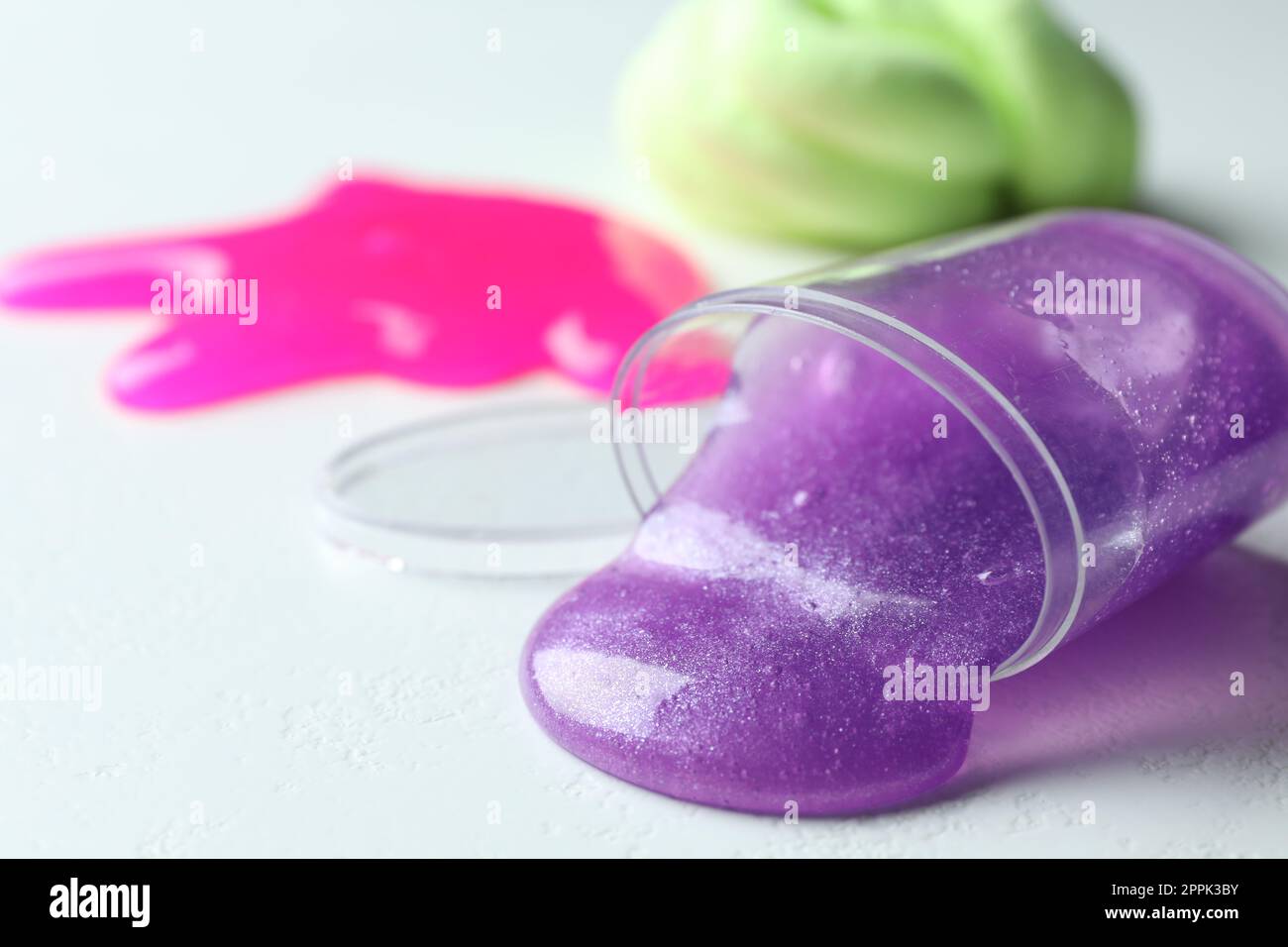 Overturned plastic container with purple slime on white background ...
