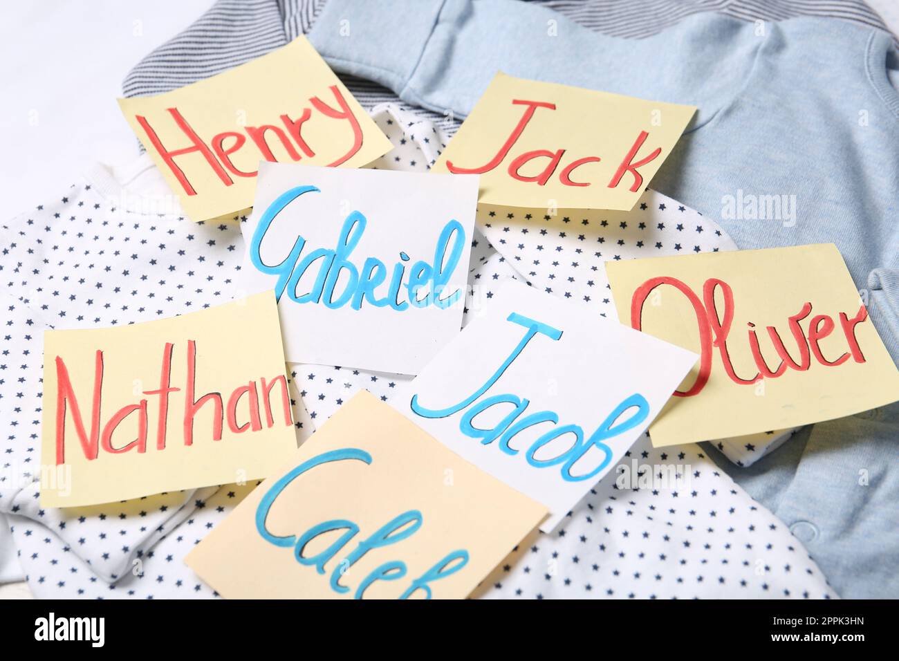 Many sticky notes with different baby names on child's clothes, closeup ...