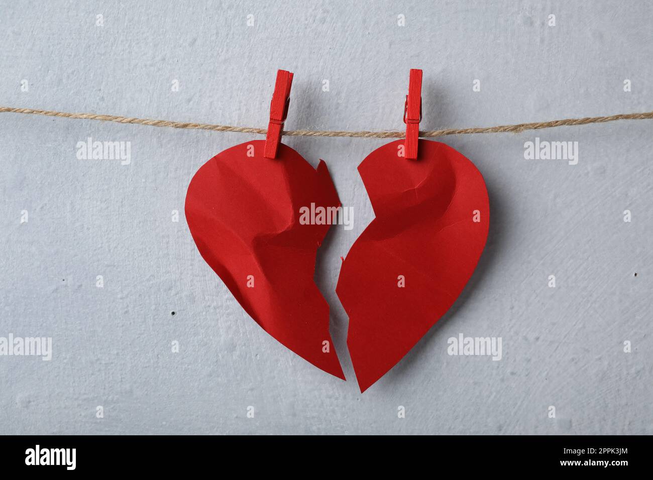 Halves of torn paper heart pinned on laundry string near light wall ... Halves of torn paper heart pinned on laundry string near light wall ...