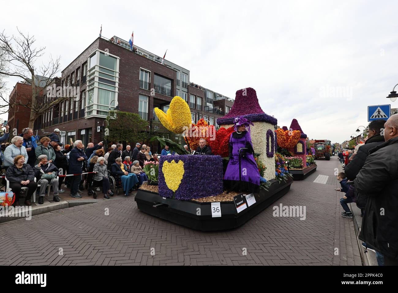 A cheerful crowd of people observe a festive parade float adorned with ...