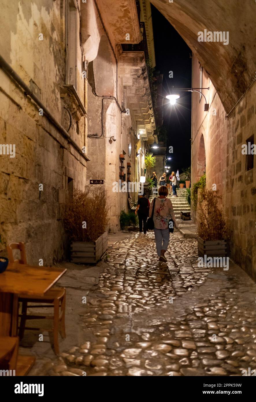 Tourists during a walk on Cobblestone street in the Sassi di Matera a ...