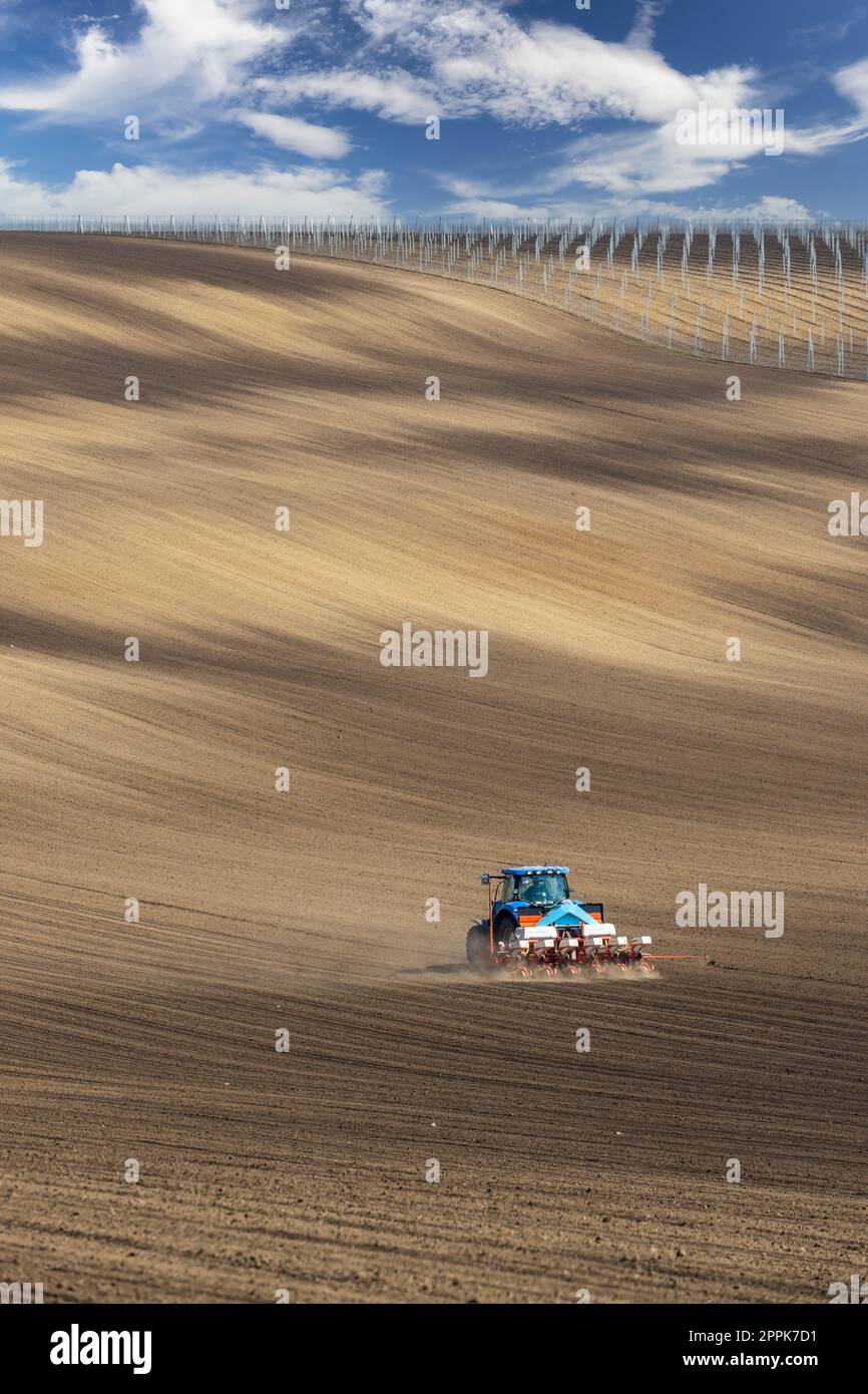 Tractor with seed drill in early spring landscape Stock Photo - Alamy