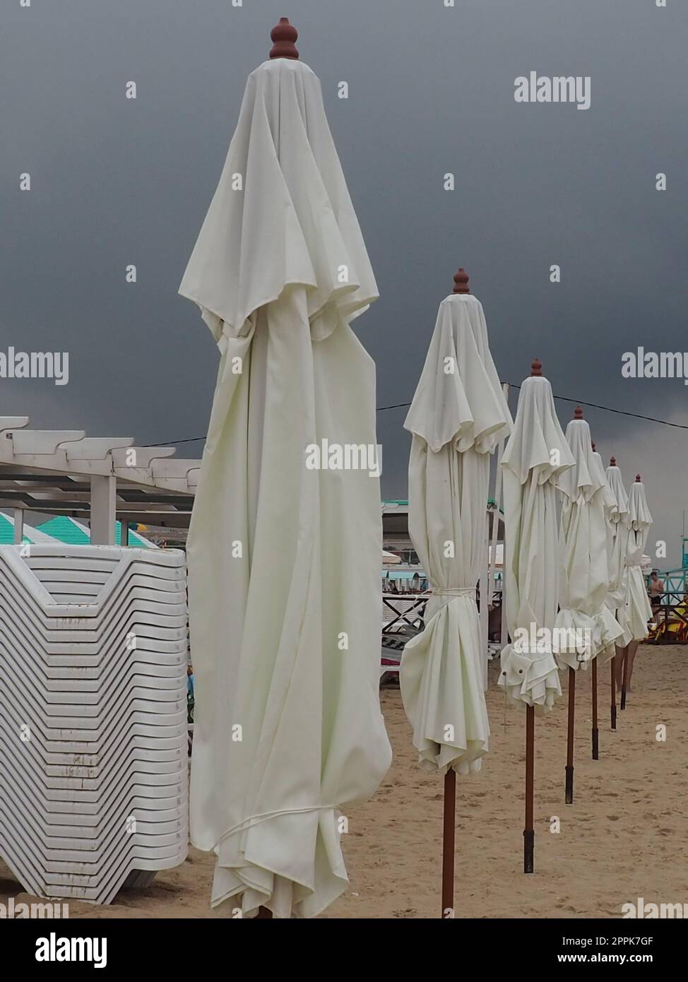 Wet sunbeds and umbrellas on the sea beach during heavy rain storm ...