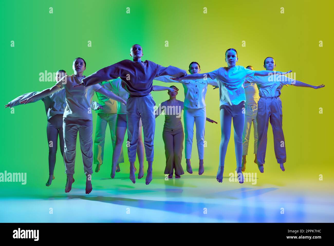 Group of teenagers, young dancers jumping together over green and ...