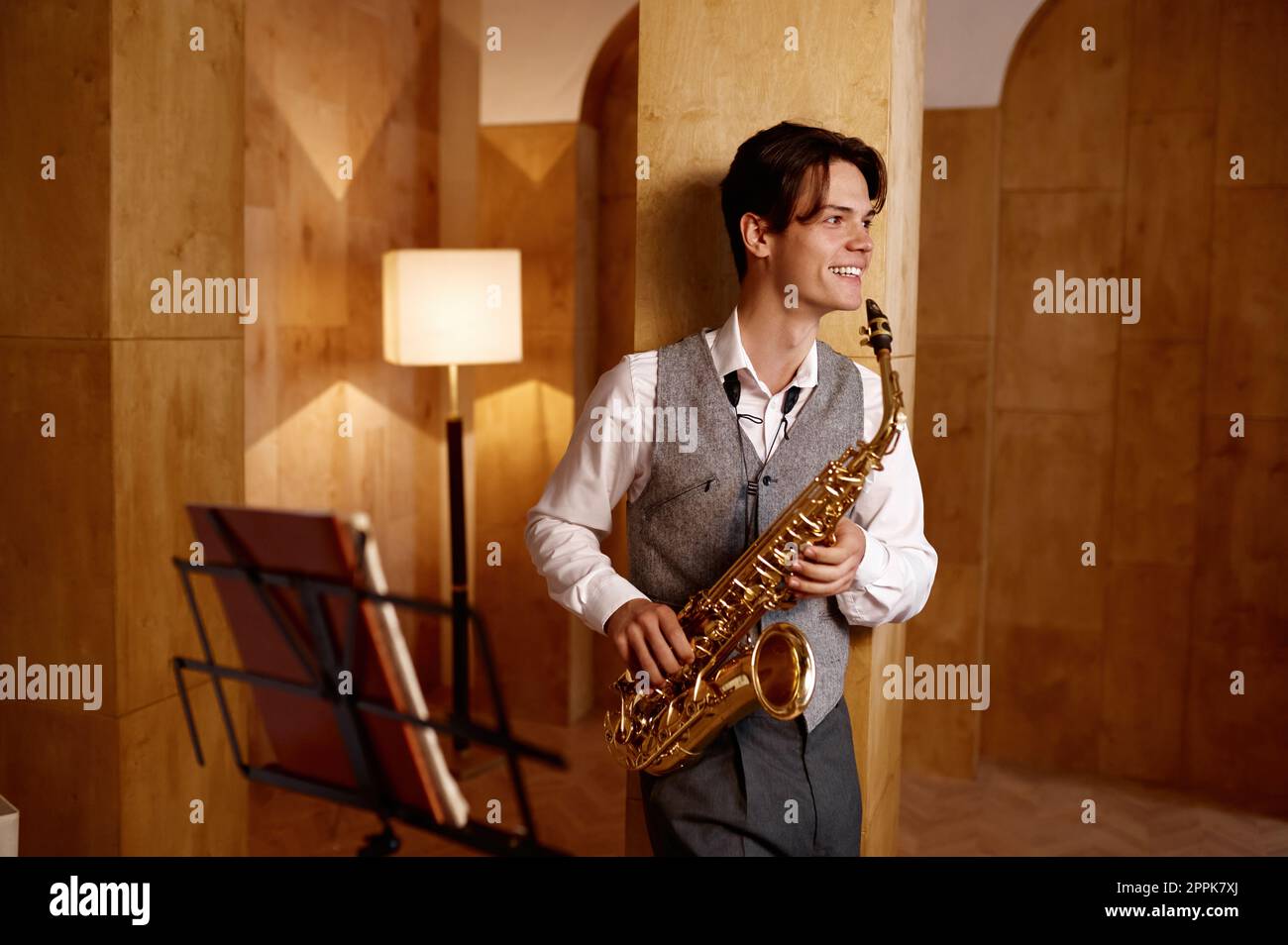 Jazz musician playing saxophone and leaning against art studio wall ...