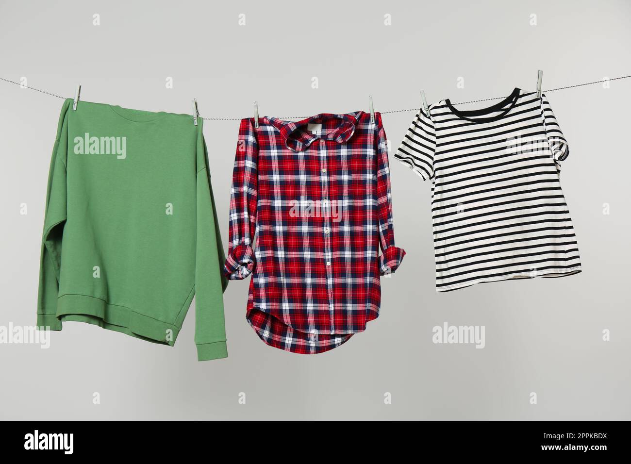 Different shirts drying on laundry line against light background Stock ...