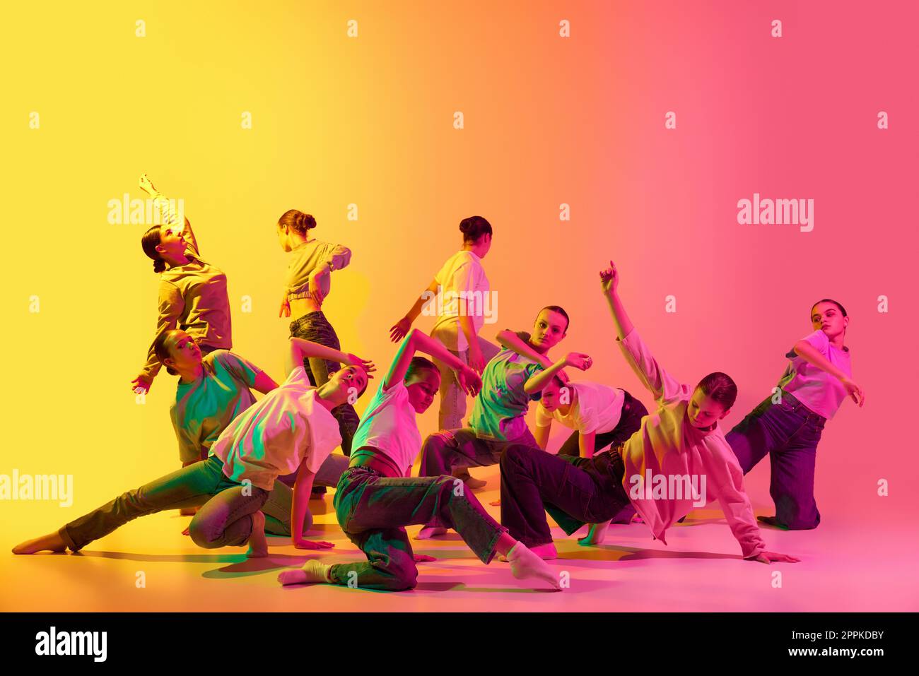 Group of teenagers, young dancers emotionally dancing together on pink ...