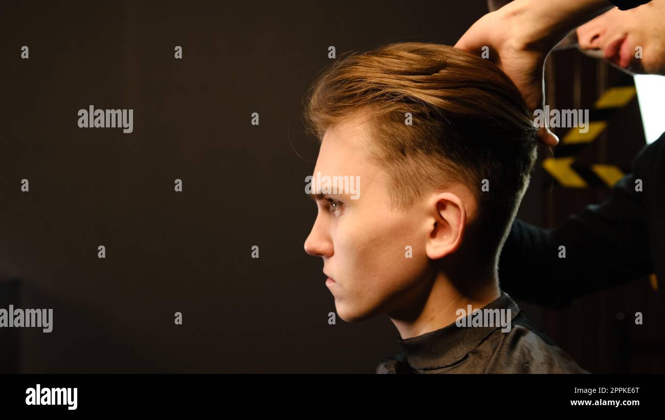 Barber shop. Man in barber's chair, hairdresser prepare his hair with ...