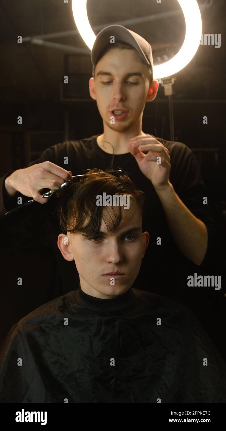 Barber master hairdresser does hairstyle and style with scissors and ...