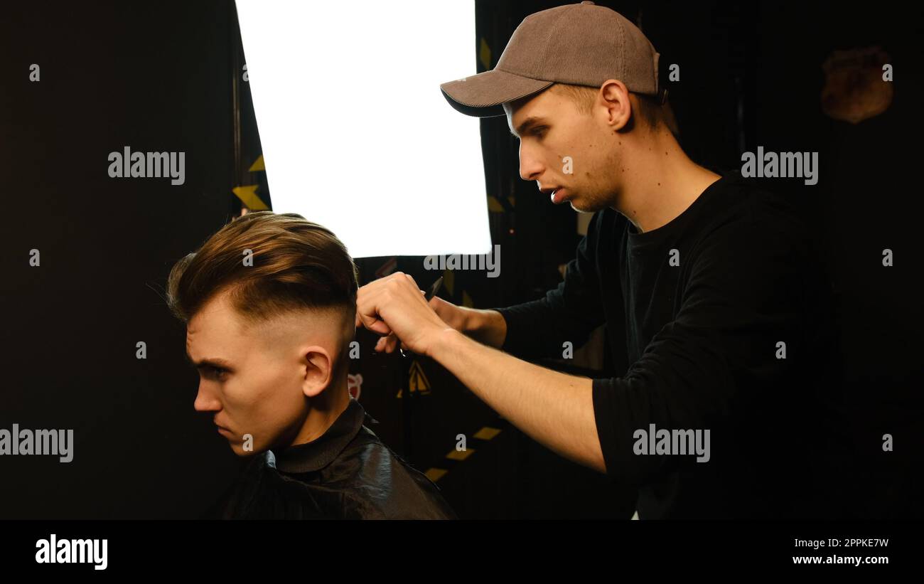 Barber master hairdresser does hairstyle and style with scissors and ...