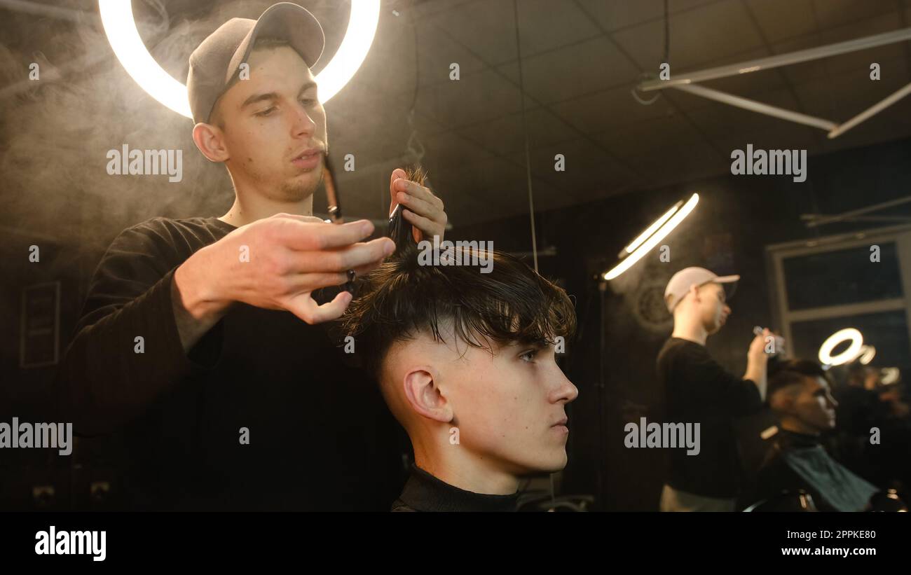 Barber master hairdresser does hairstyle and style with scissors and ...