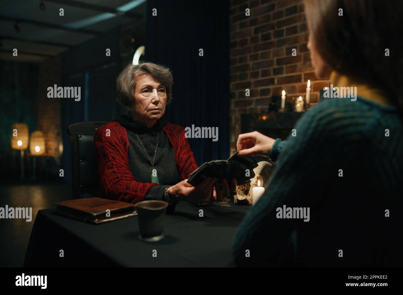 Old mature soothsayer holding divination tarot cards in front of client ...