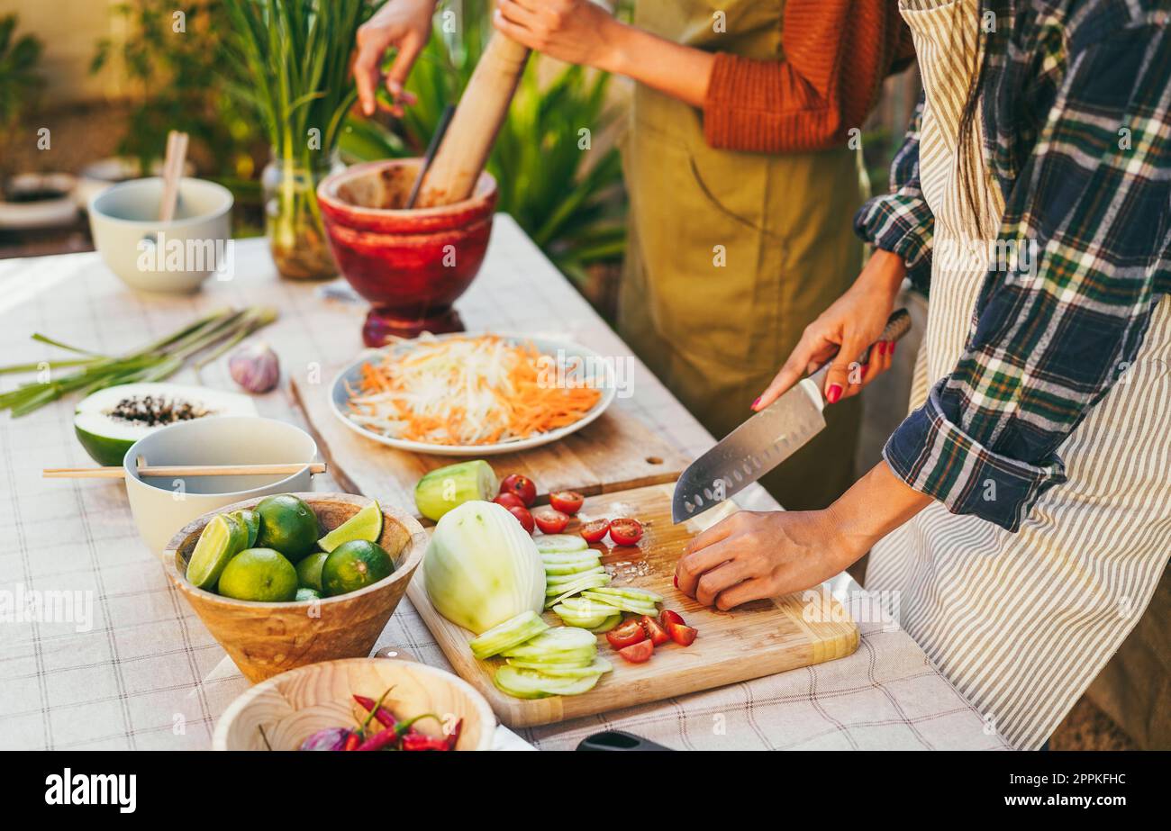 Asian family cooking thai dinner together while preparing papaya salas ...