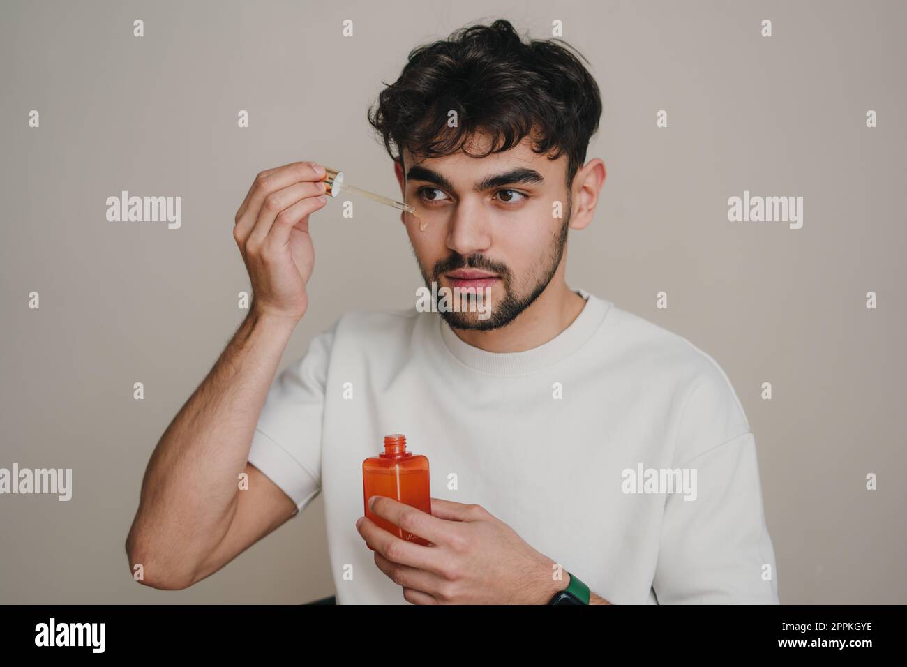 Close up view of a young caucasian man applying moisturizing serum with ...