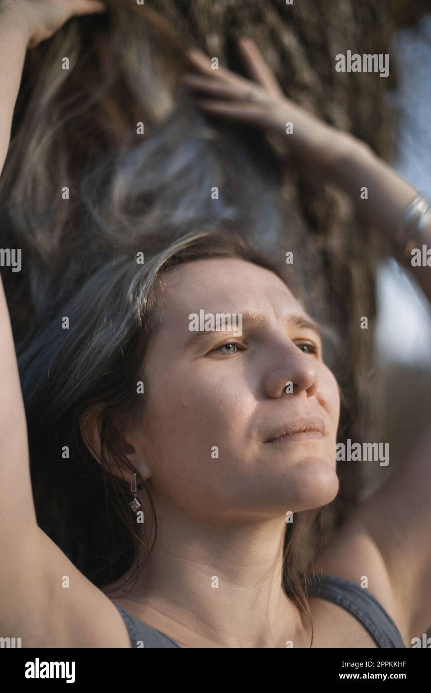 Close up adult genuine woman with ruffled hair posing near tree ...