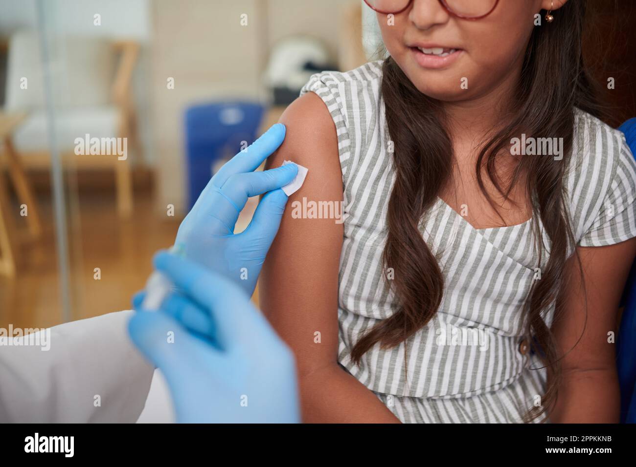 Closeup image of doctor wiping injection site on arm of patient with ...