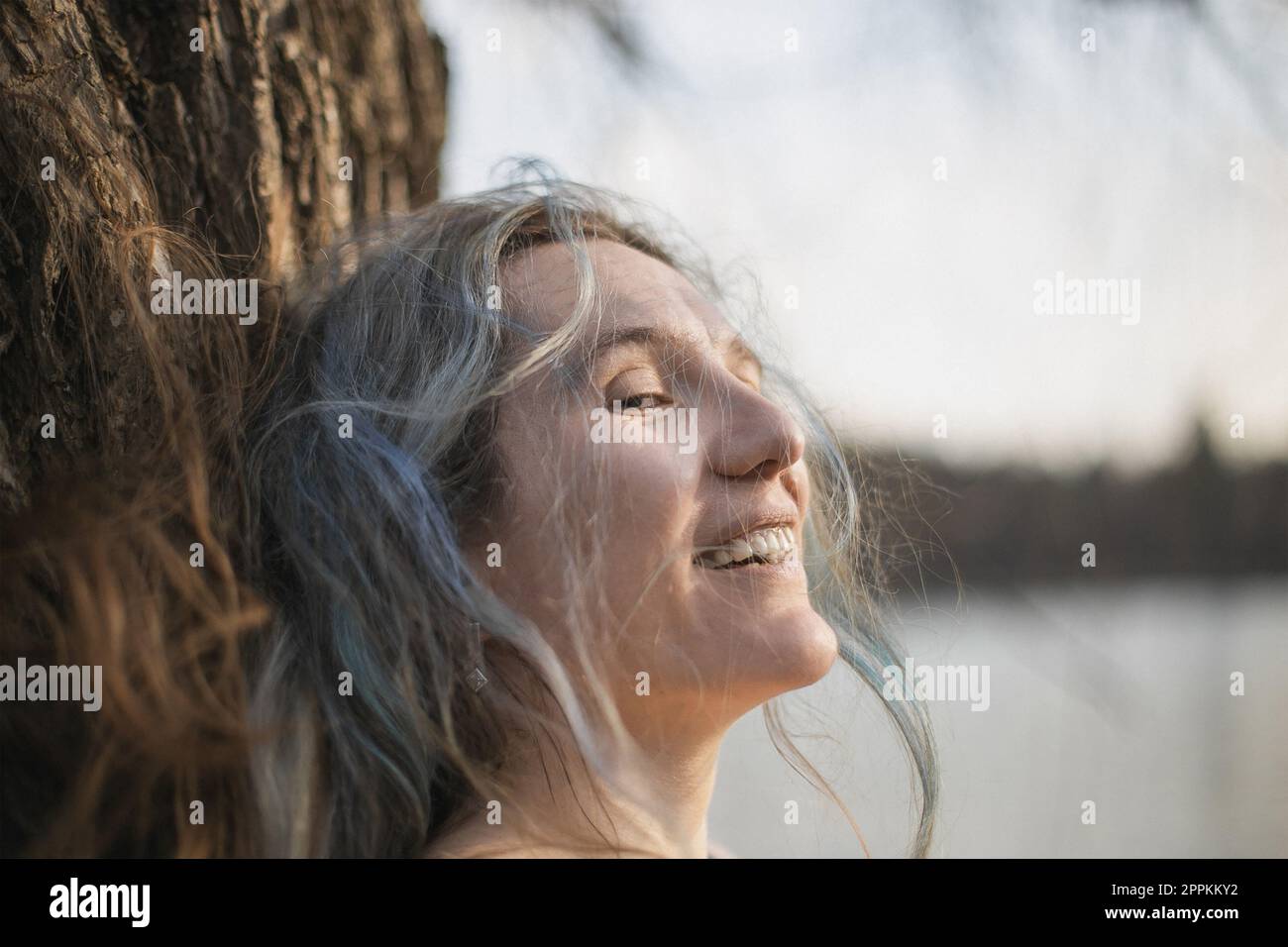 Close up woman with gray ruffled hair laughing and looking sideway ...