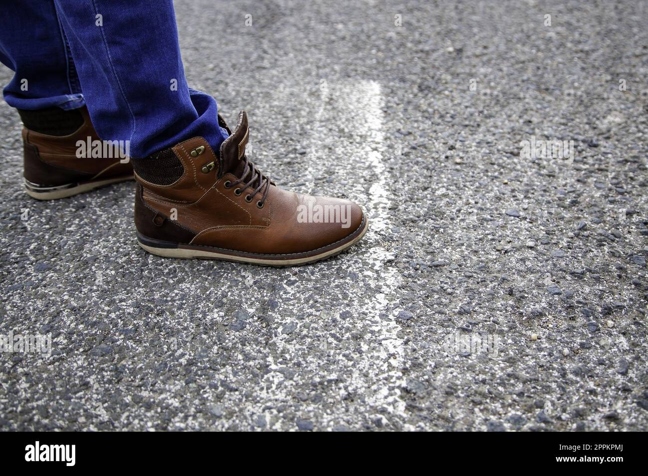 Feet stepping on asphalt line Stock Photo - Alamy