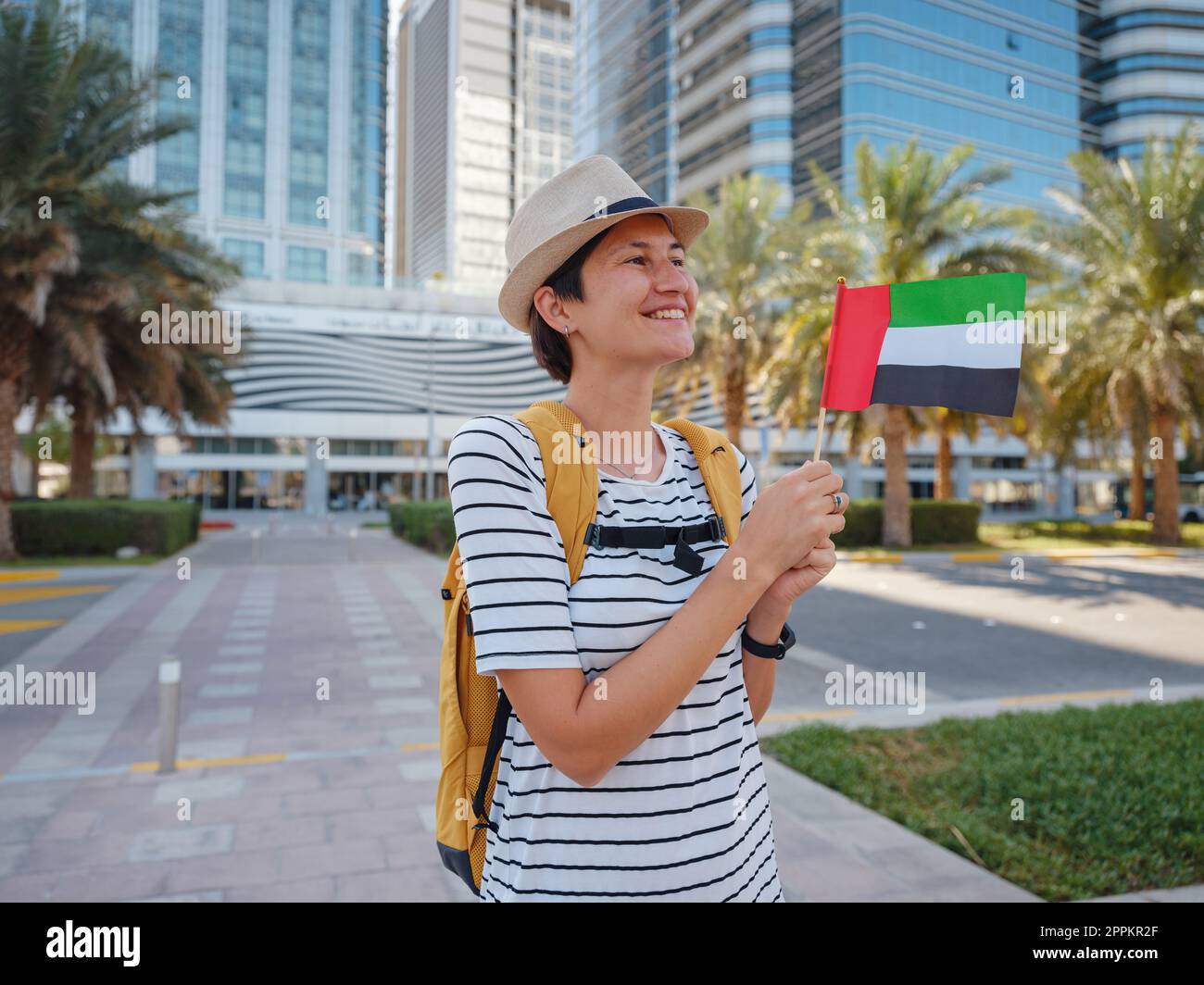 Happy young asian female traveler with backpack and hat with UAE flag ...