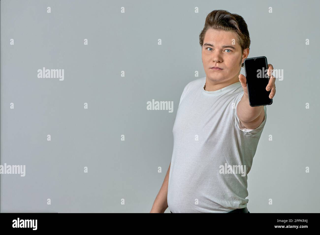 A man at arm's length shows a phone screen on a gray background Stock ...