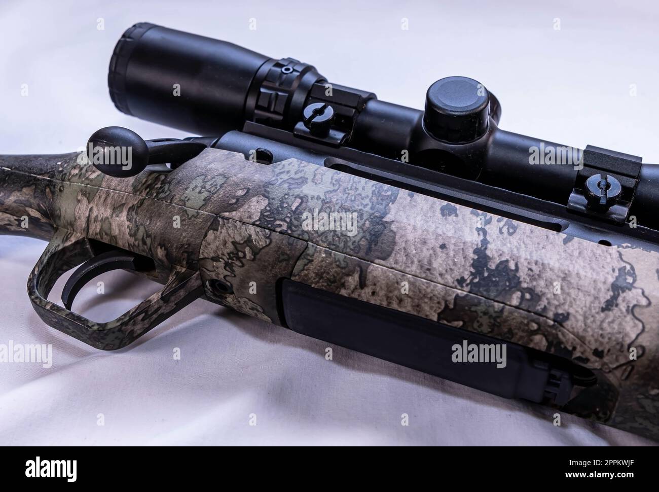 A high power deer rifle with a camo synthetic stock on a white ...