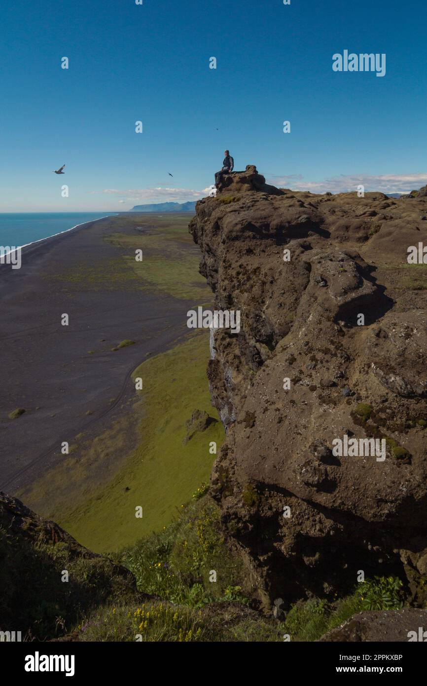 Man sitting on steep cliff landscape photo Stock Photo - Alamy