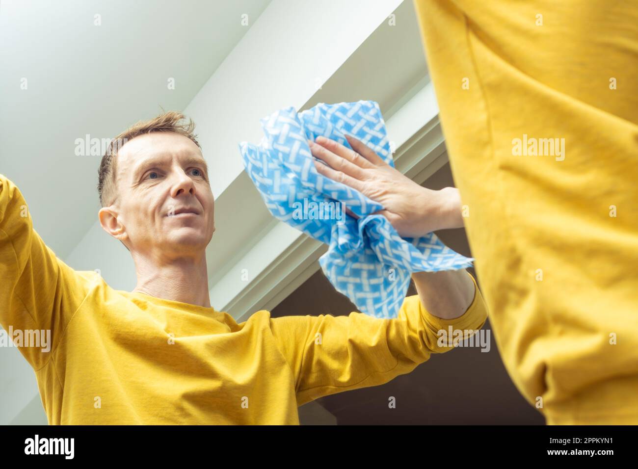 Mature man wiping room mirror with rag, from below view. Happy man rub ...