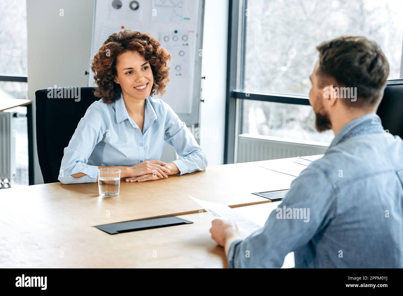 African American woman is hired on a new job. Two people sitting at a ...