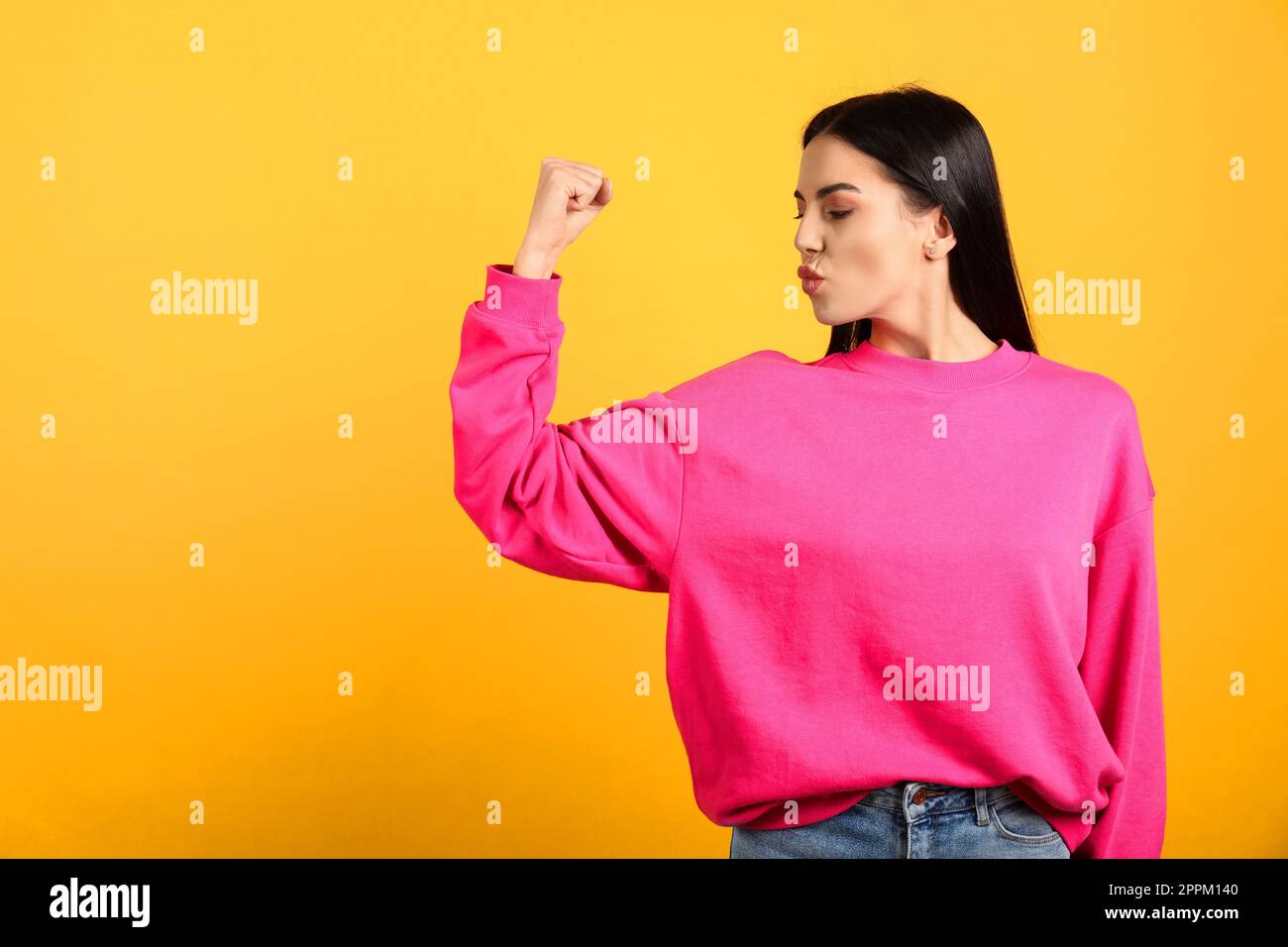 Strong woman as symbol of girl power on yellow background, space for ...