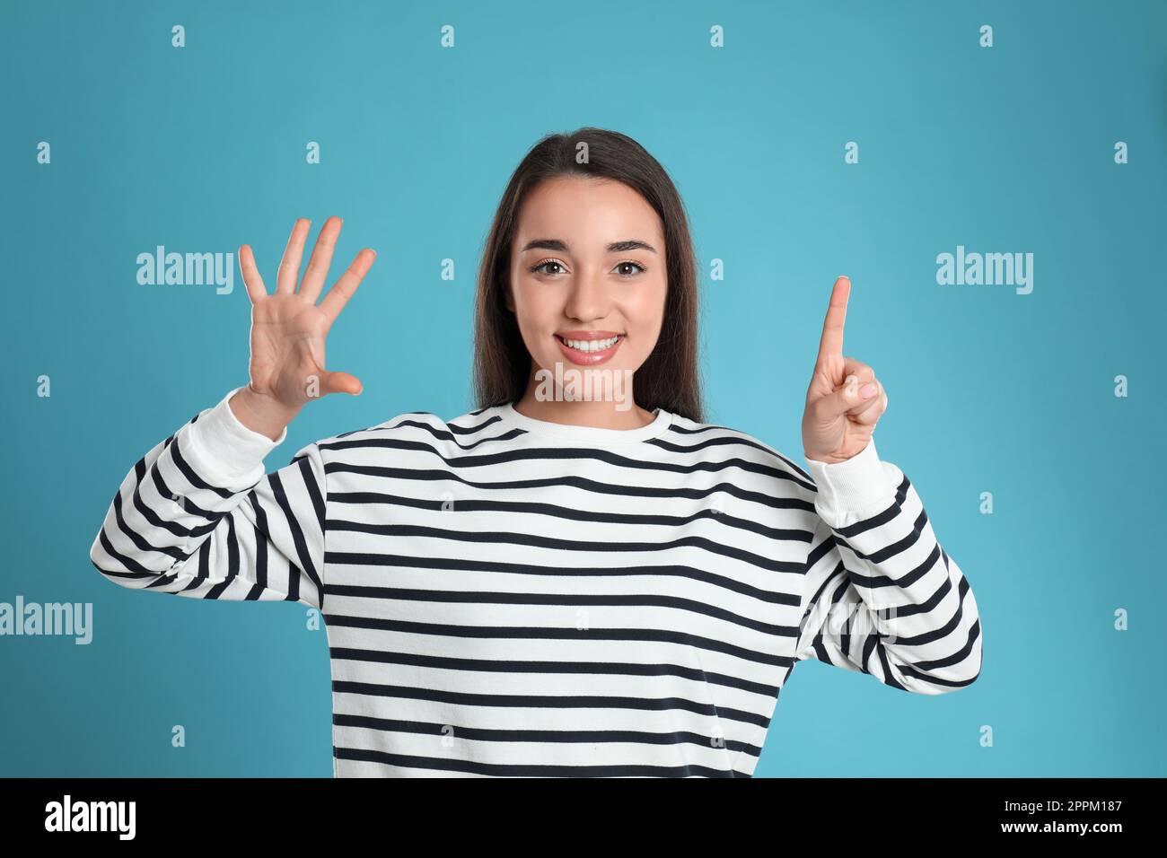 Woman showing number six with her hands on light blue background Stock ...