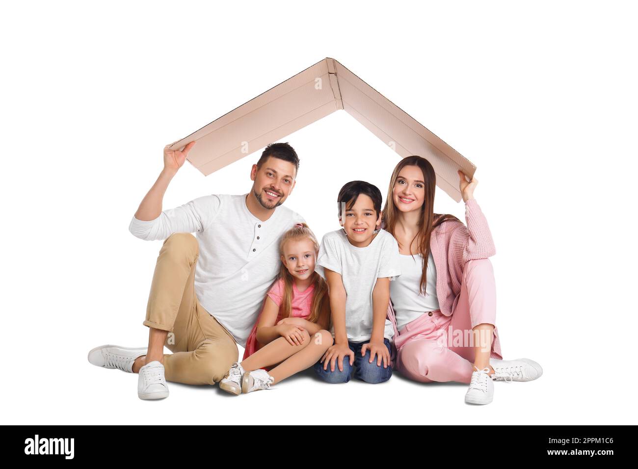 Happy family sitting under cardboard roof on white background ...