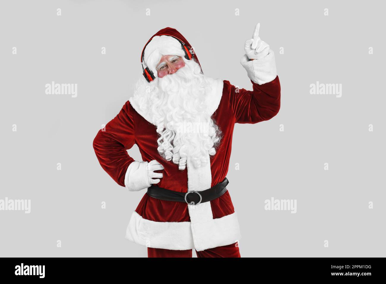 Santa Claus with headphones listening to Christmas music on light grey ...