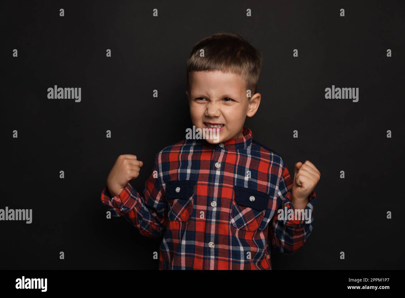 Angry little boy on black background. Aggressive behavior Stock Photo ...