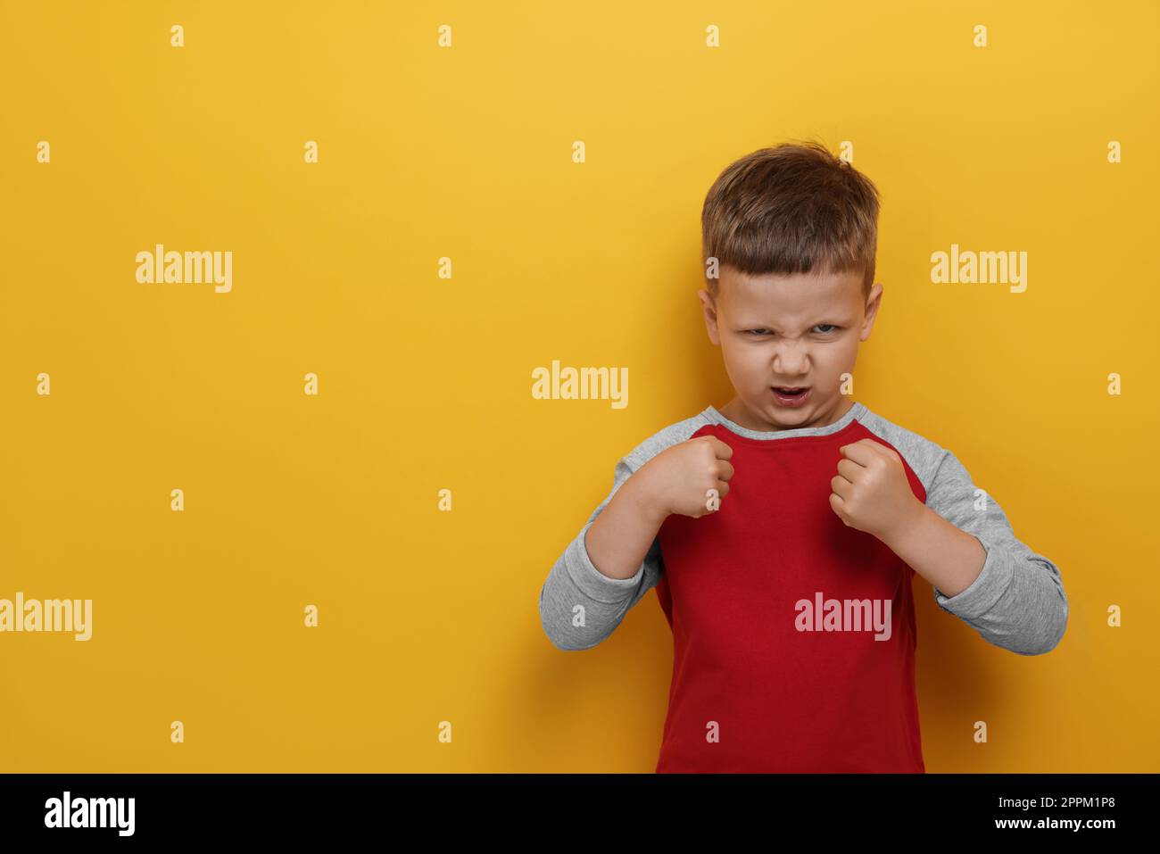 Angry little boy on yellow background, space for text. Aggressive ...