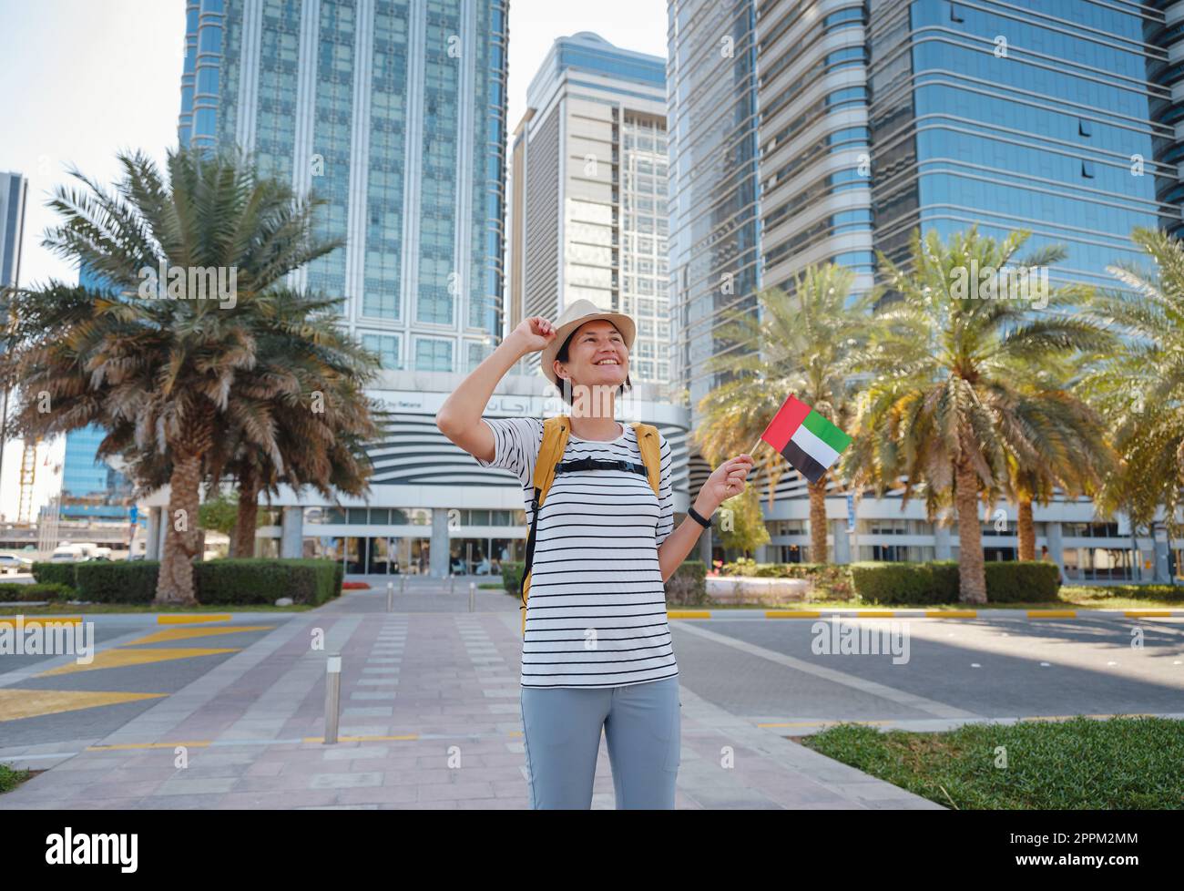 Happy young asian female traveler with backpack and hat with UAE flag ...
